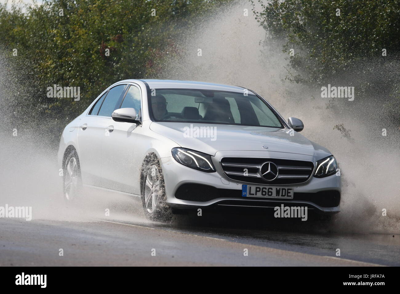 Cars splashing through puddles on wet roads in Bedfordshire, England ...