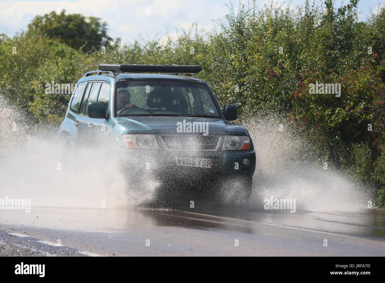 Cars splashing through puddles on wet roads in Bedfordshire, England ...