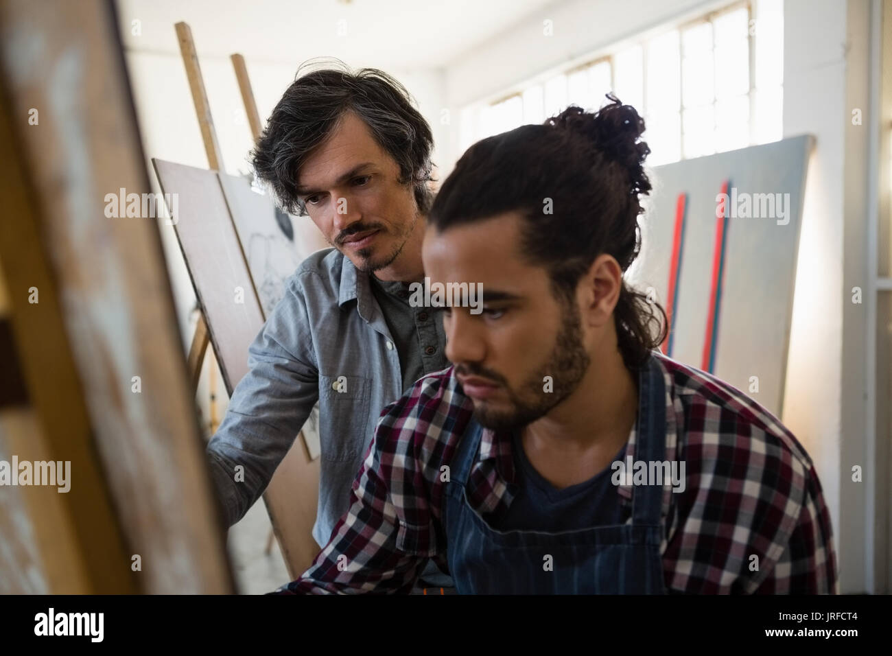 Artist assisting man painting in art class Stock Photo - Alamy