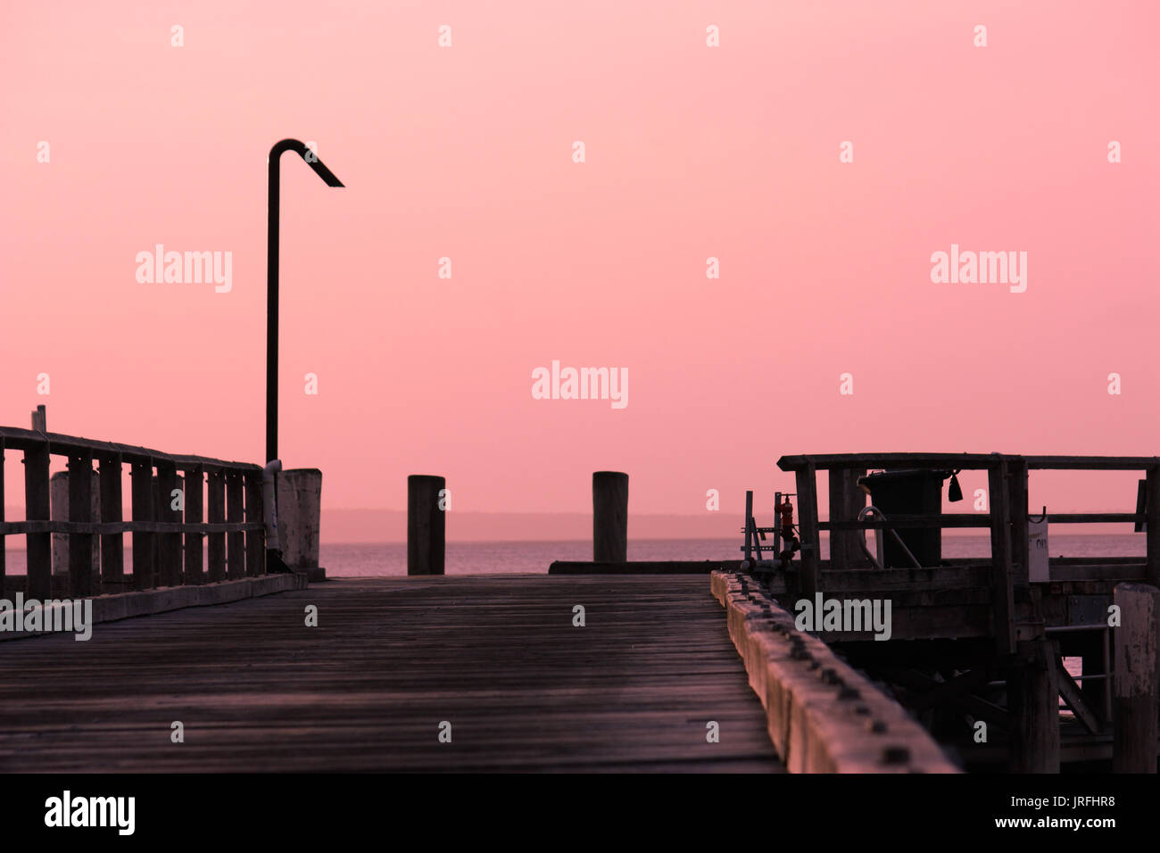 Pink sunset hues over wooden jetty wharf on Fraser Island Queensland ...