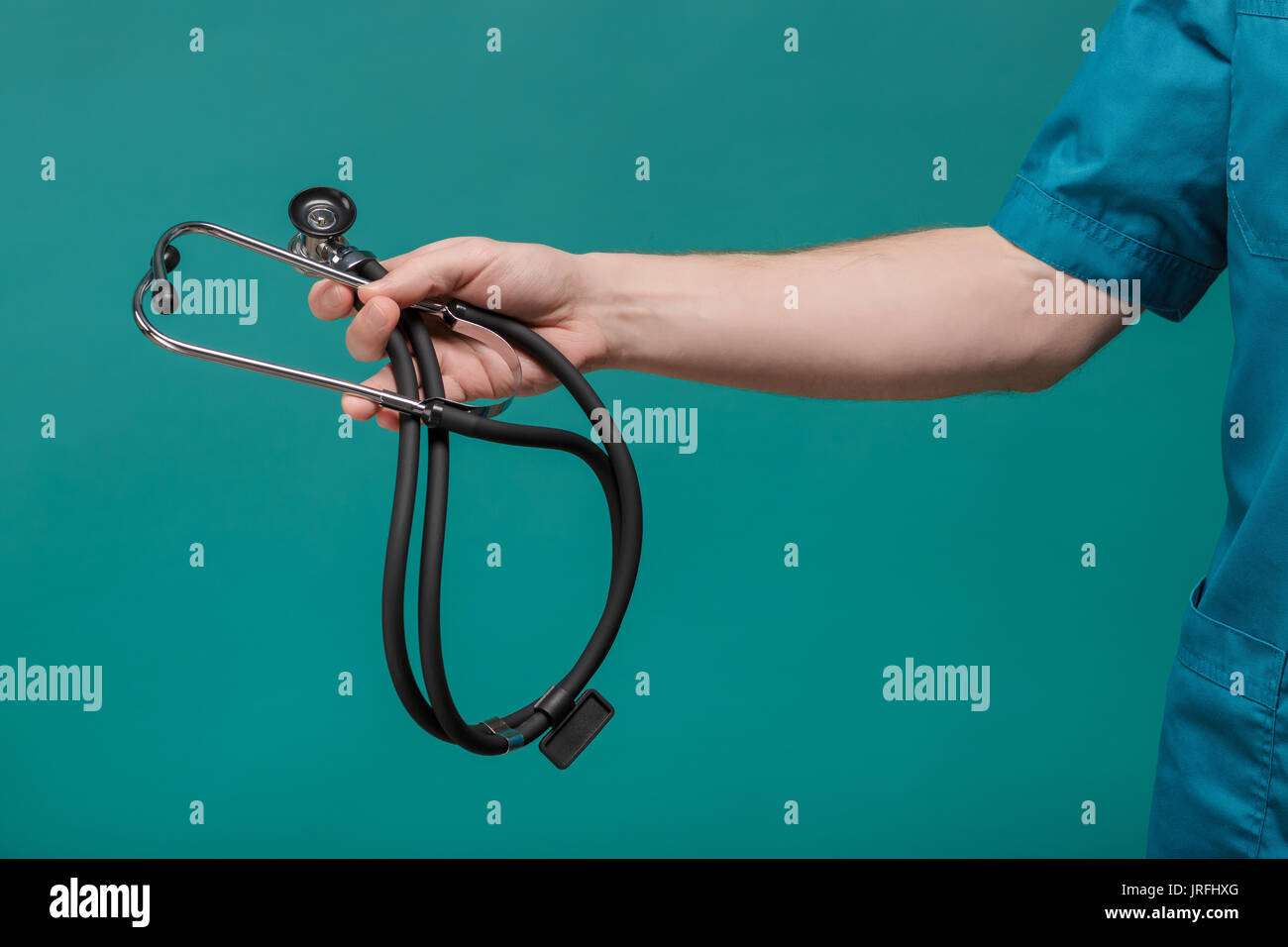 male doctor holding his stethoscope in hand on the blue background ...