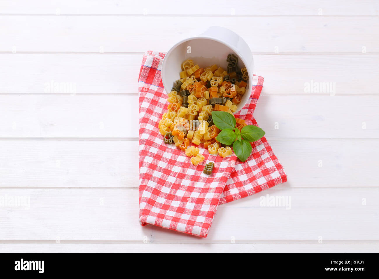 bowl of raw colored pasta spilt out on checkered dishtowel Stock Photo ...