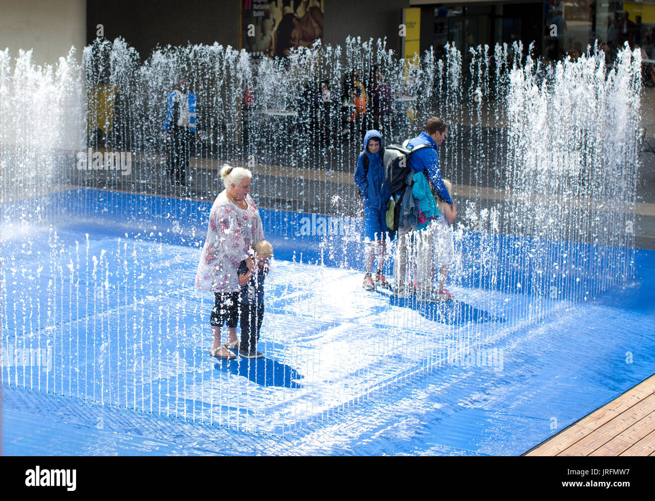 People enjoy a splash in the water fountain at the Southbank, London ...