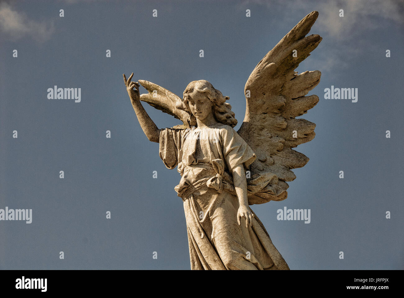 An angel statue with arm raised under a blue sky Stock Photo - Alamy