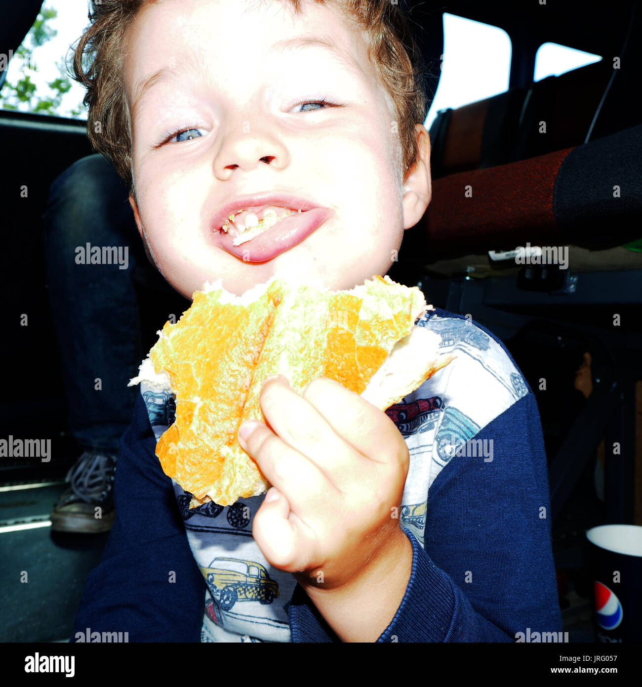 Young boy eating ham baguette Stock Photo - Alamy