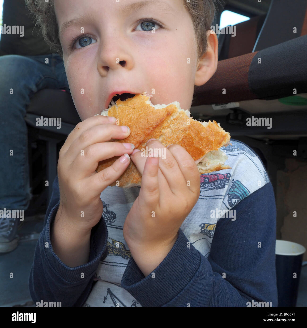 Young boy eating ham baguette Stock Photo - Alamy