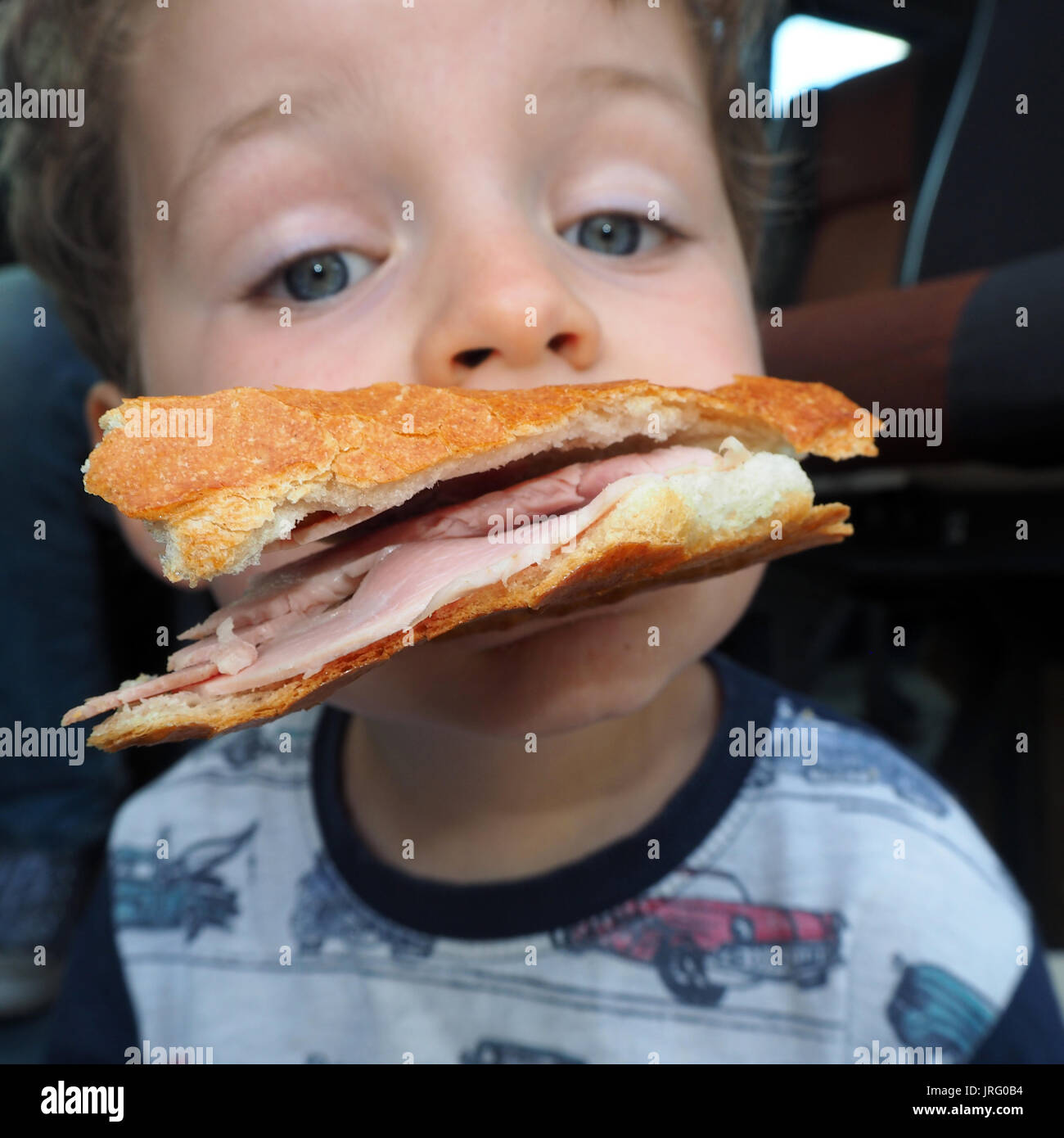 Young boy eating ham baguette Stock Photo - Alamy