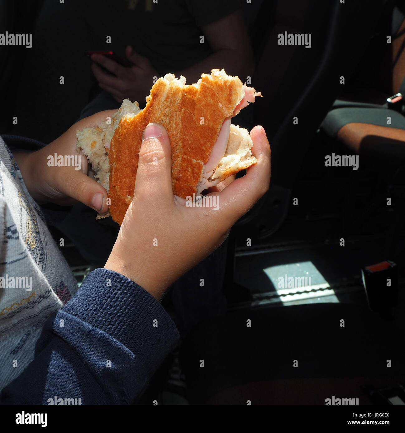 Young boy eating ham baguette Stock Photo - Alamy