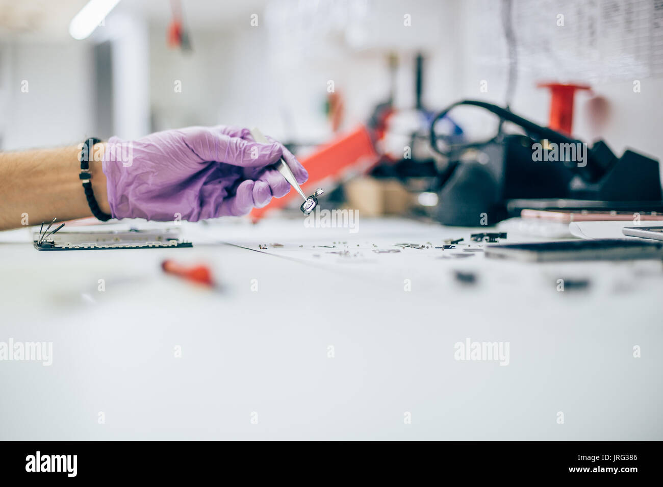 Technician with tweezers carries parts of the mobile phone during the ...