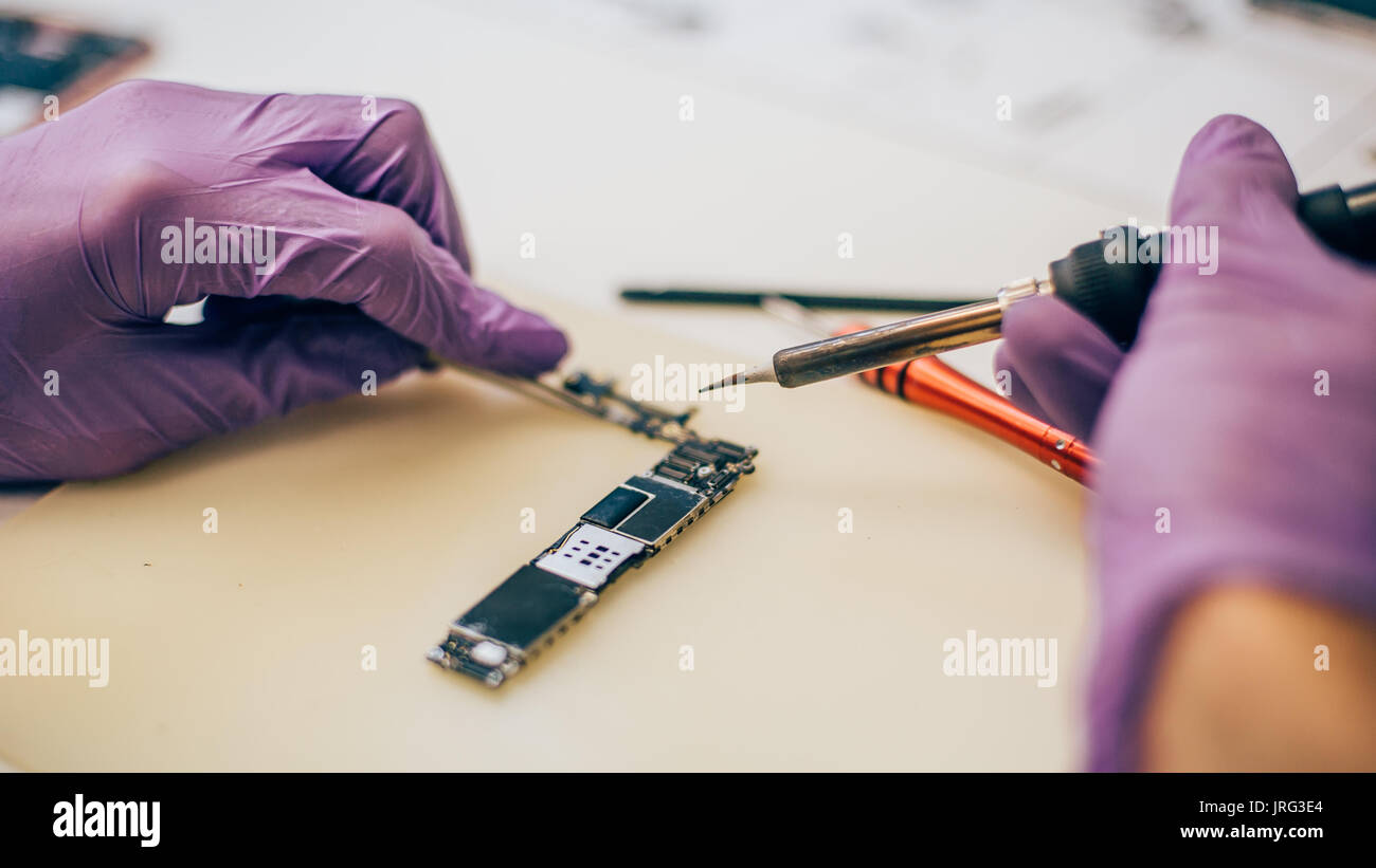 Technician repair microchip and motherboard of mobile phone in ...