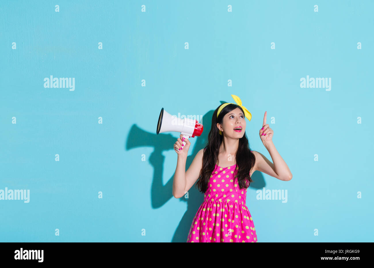 beautiful smiling woman pointing above showing empty area and holding ...