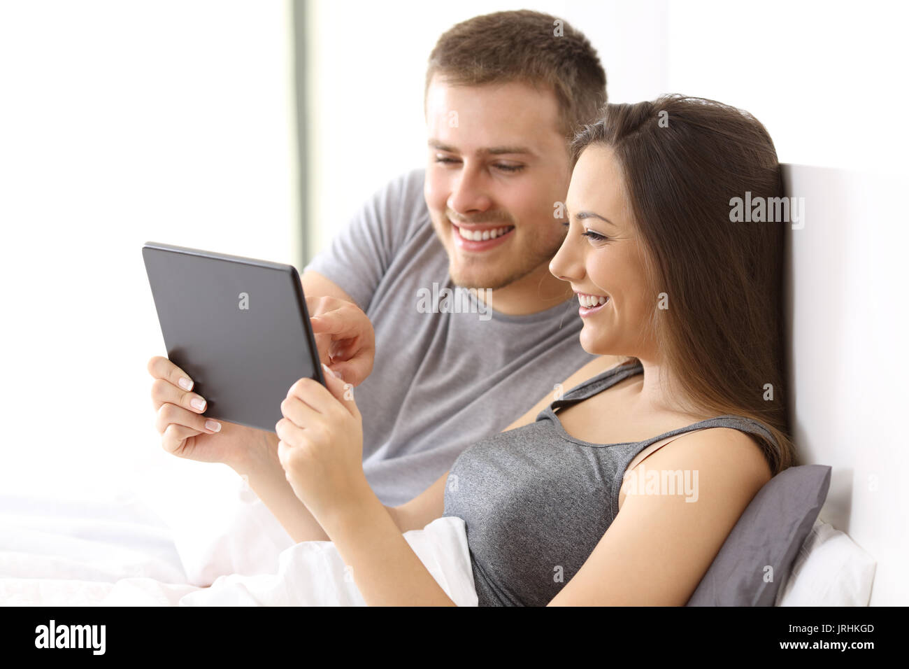 Couple watching media content together on line in a tablet on the bed ...