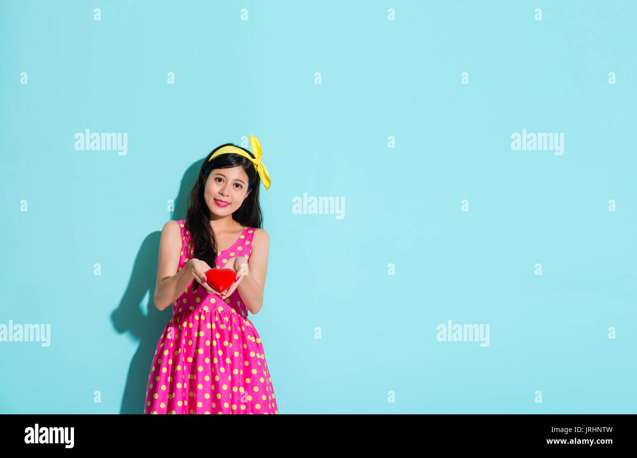 happy beauty lady presenting heart shaped model standing in blue ...