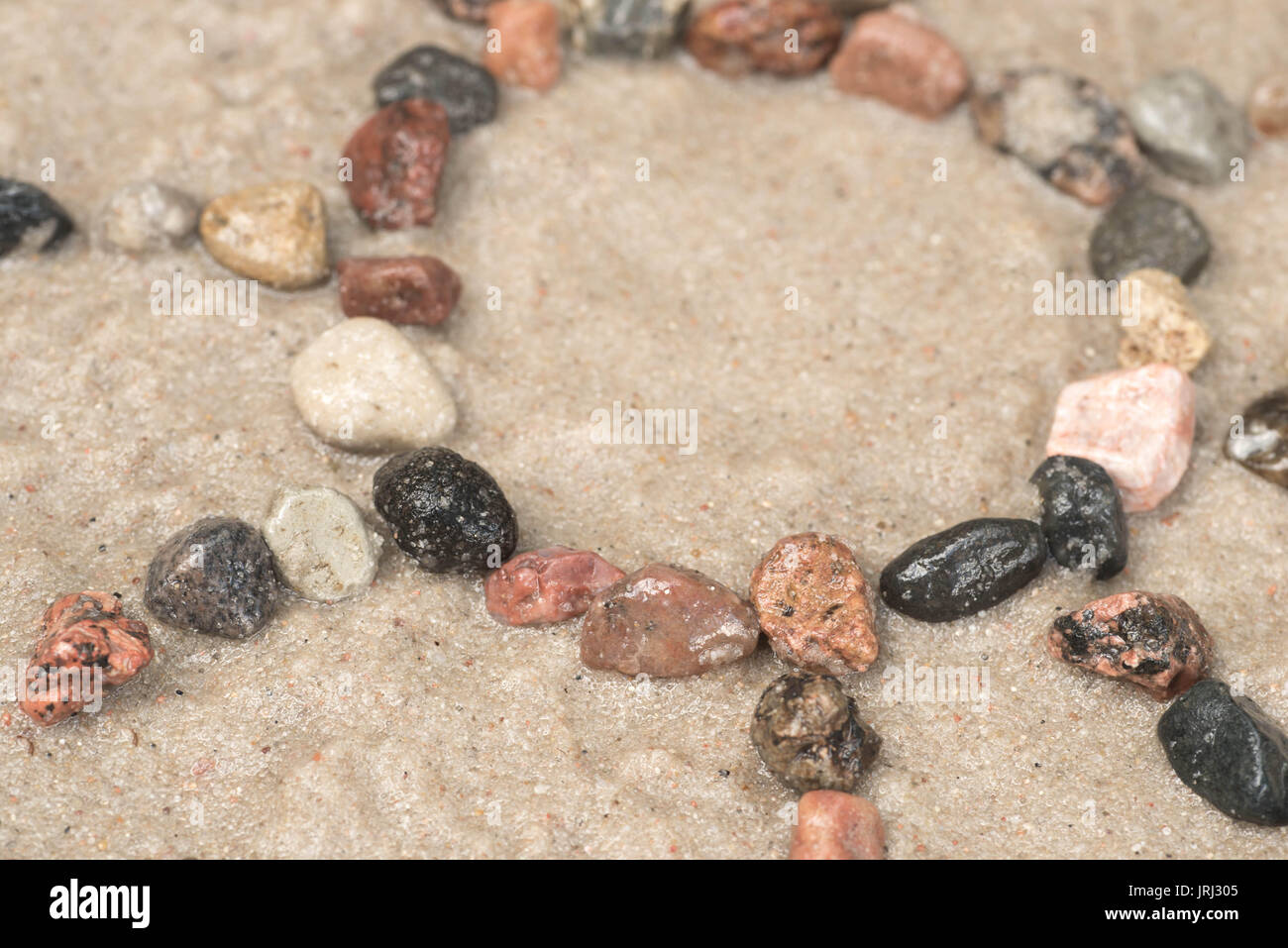 pebble sun sign on sand background Stock Photo - Alamy