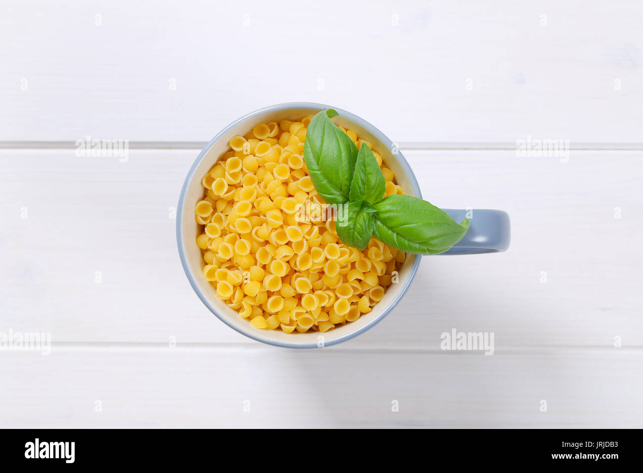 cup of small pasta shells on white wooden background Stock Photo - Alamy