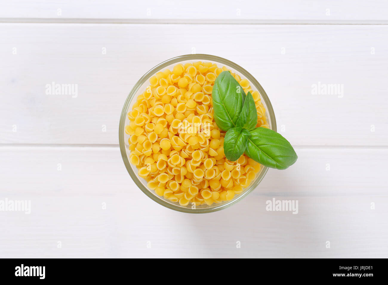 glass of small pasta shells on white wooden background Stock Photo - Alamy
