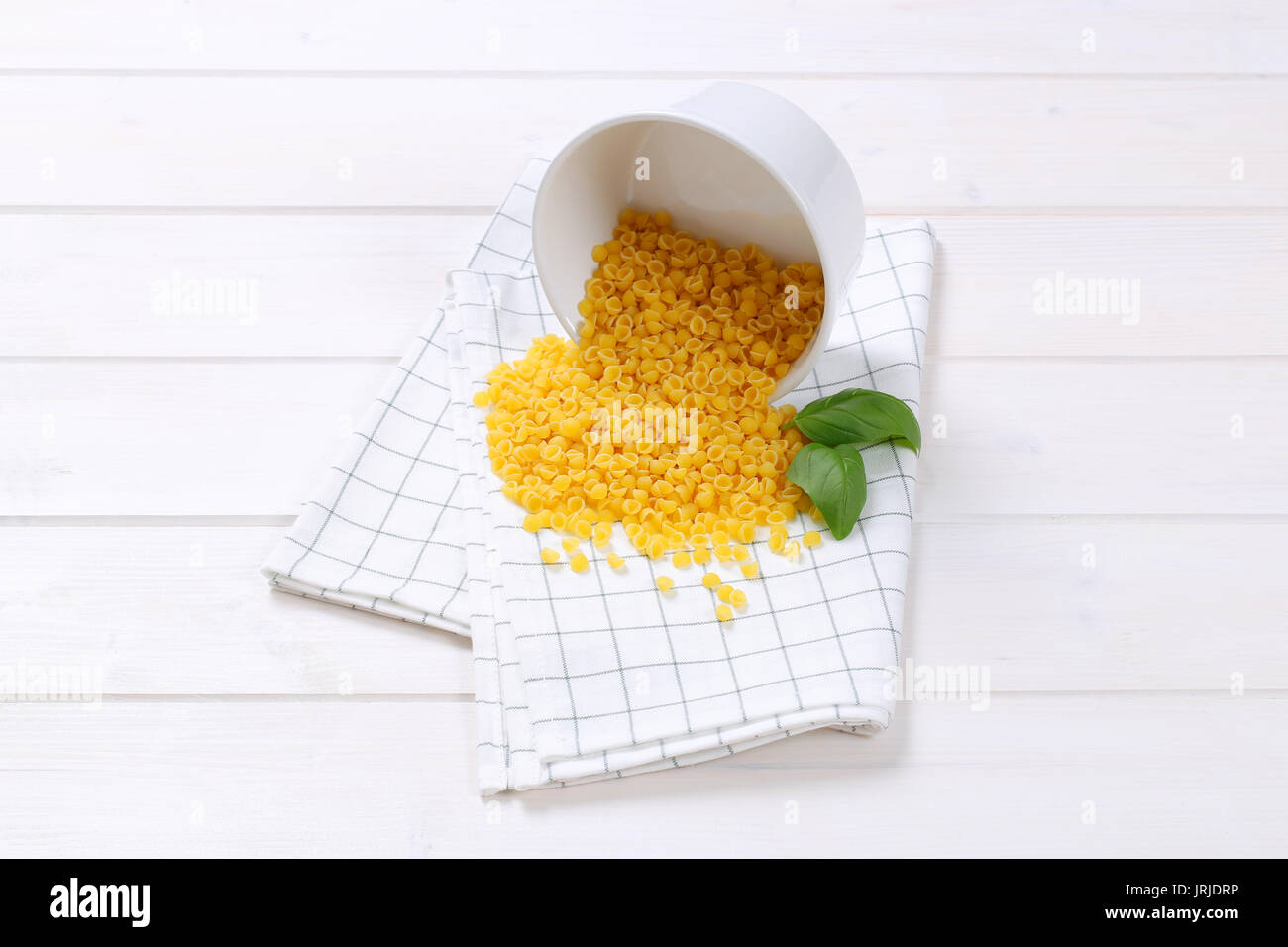 bowl of small pasta shells spilt out on checkered dishtowel Stock Photo ...