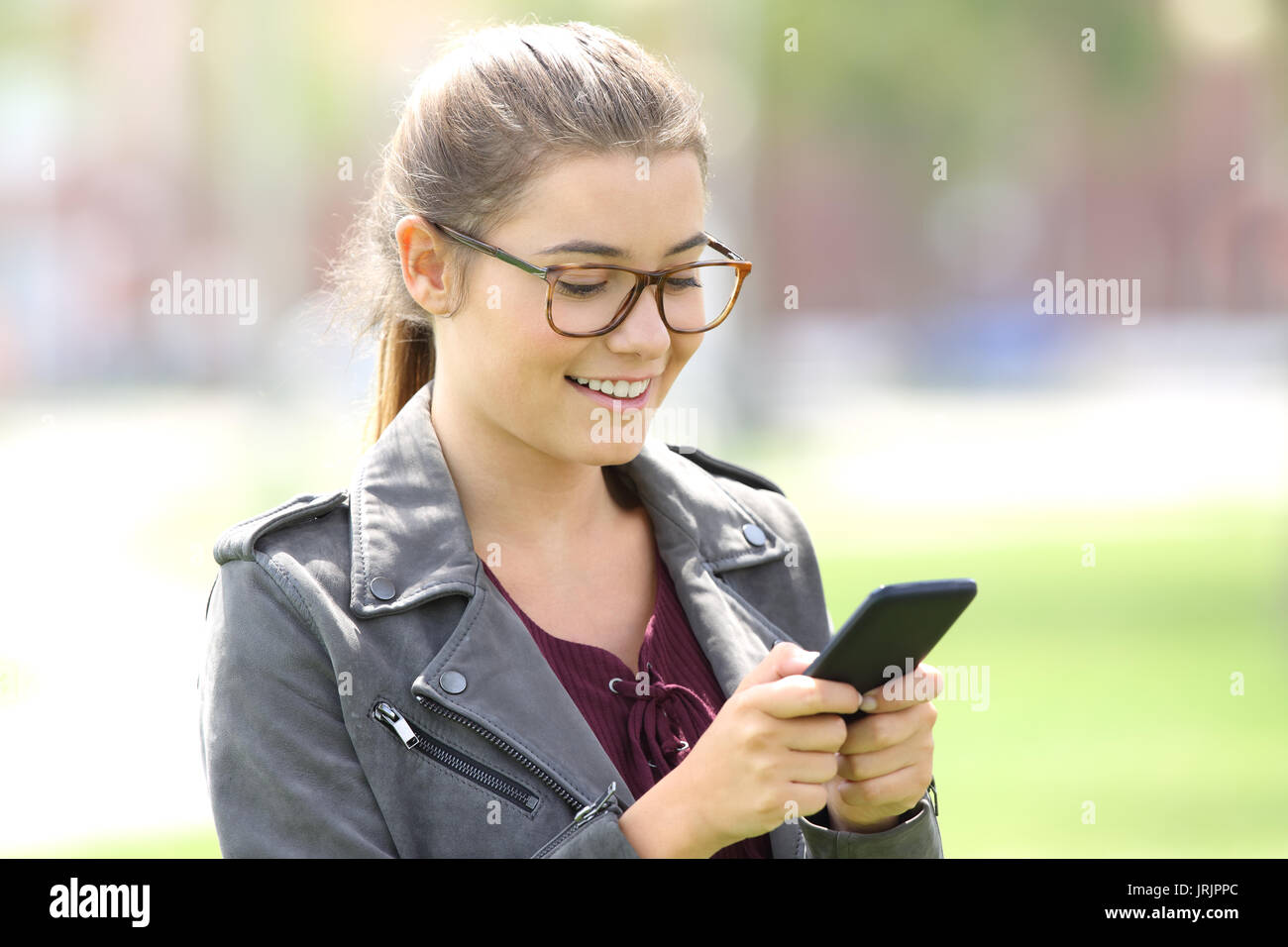 Portrait Of A Single Happy Girl Wearing Eyeglasses Texting In A Mobile