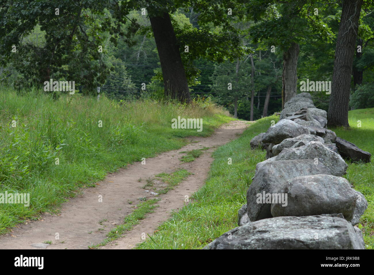 A dirt road and stone wall at the Concord National Historic Site near ...