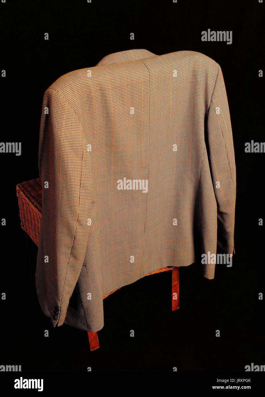 Tweed jacket hanging over the back of a chair portrait format with copy ...