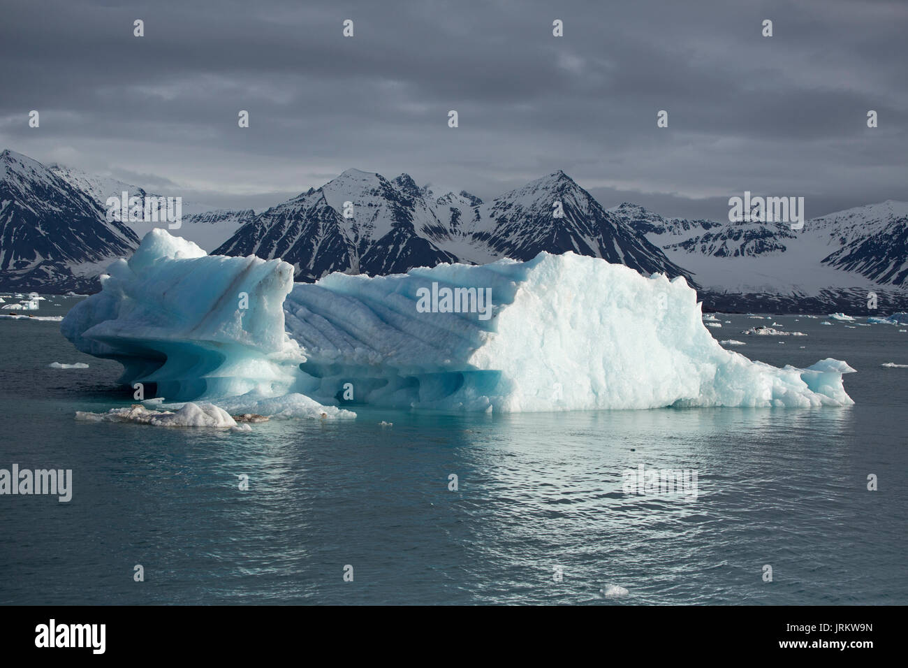 Ice formation floating on sea with snow covered mountains in background ...