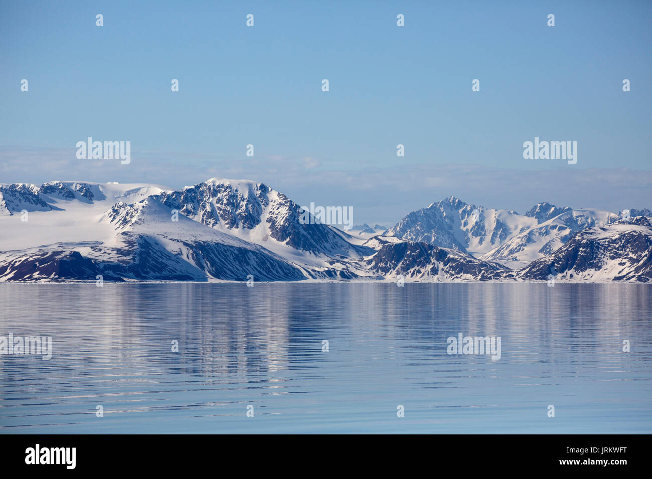 Snow covered mountains reflected in calm sea. Taken in June, Andoyane ...