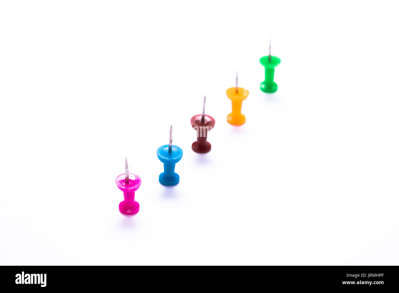 Coloured office pins in a row white isolated Stock Photo - Alamy