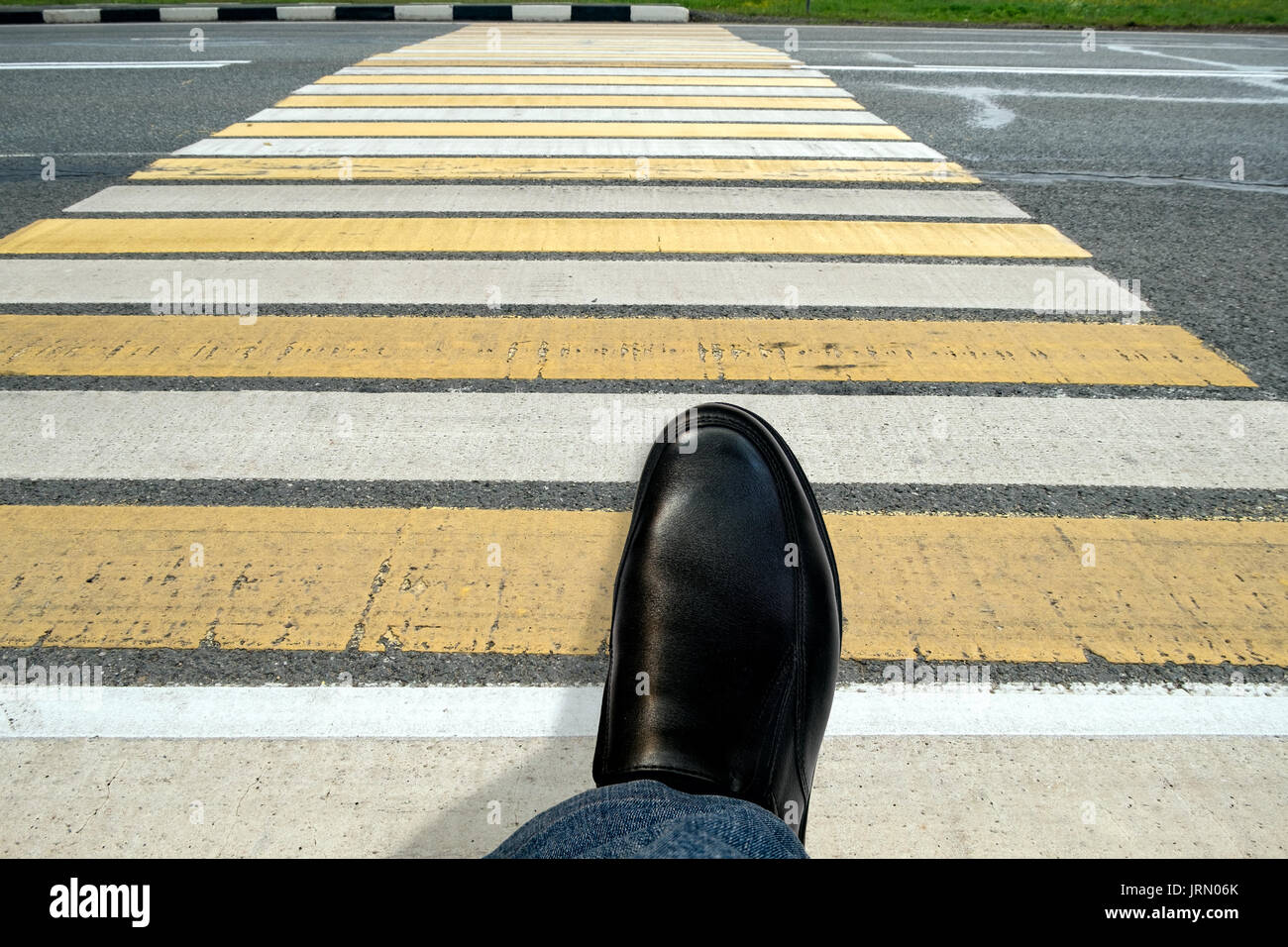A person crosses the road. The pedestrian steps his foot on the white ...