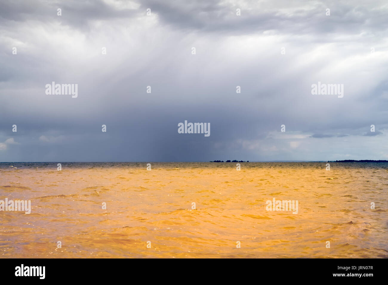 Thundercloud over the yellow river. Horizontal frame. A dark blue cloud ...