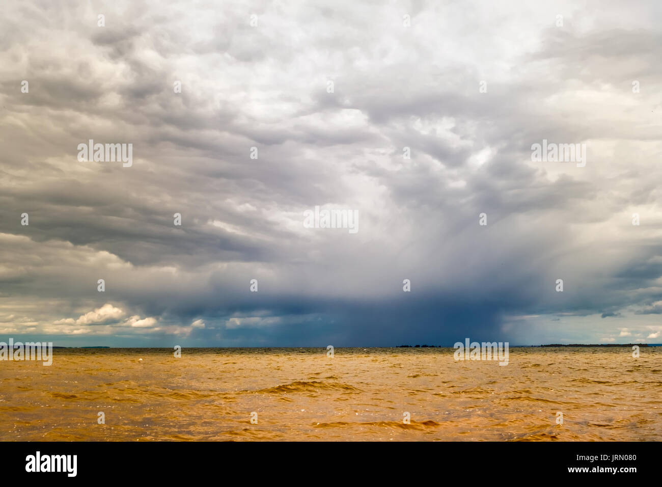 Thundercloud over the yellow river. Horizontal frame. A dark blue cloud ...
