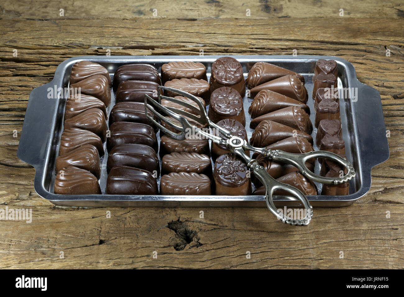 tray with Belgian chocolate pralines and pastry tong on rustic wooden ...