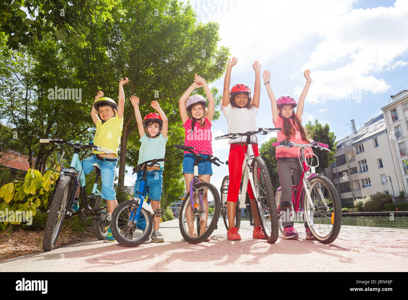 Group of five age-diverse kids in safety helmets standing in line with ...