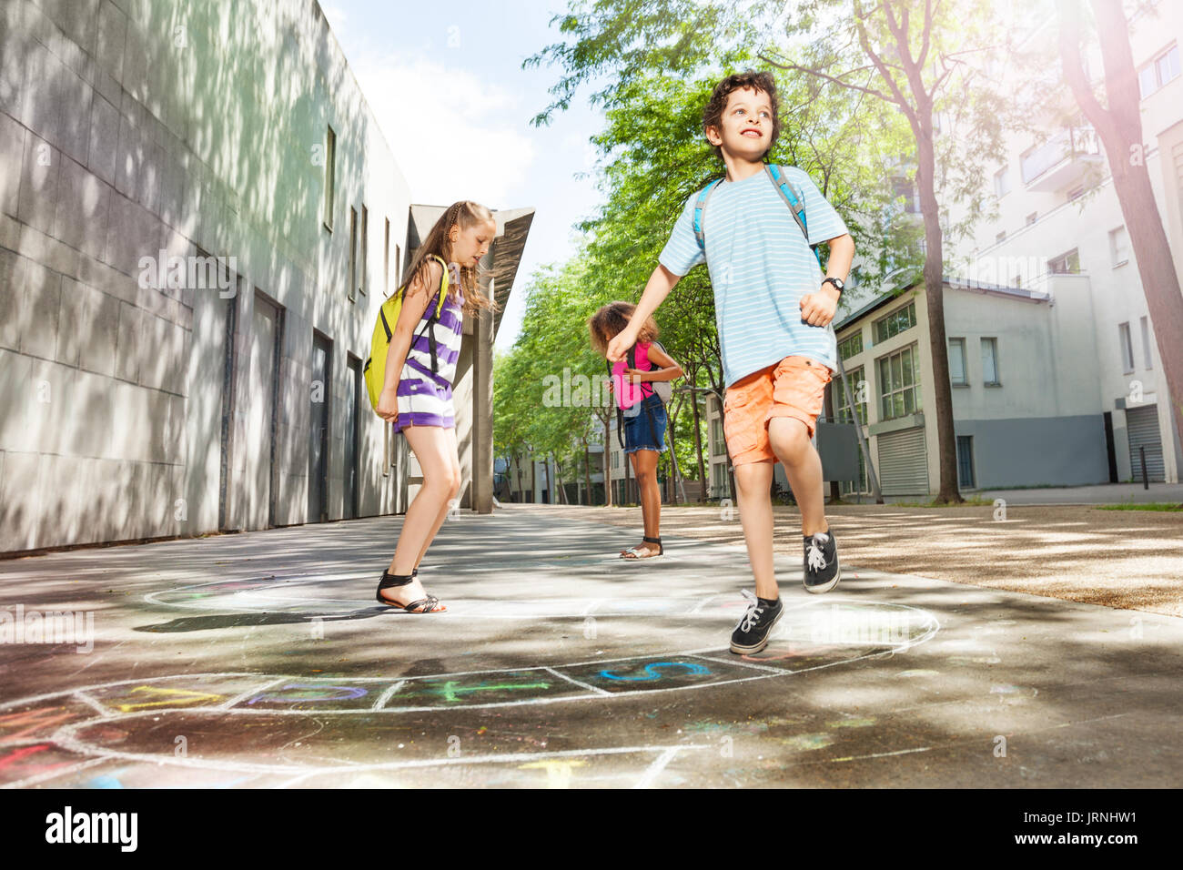 Portrait of children jumping on the hopscotch squares and numbers ...