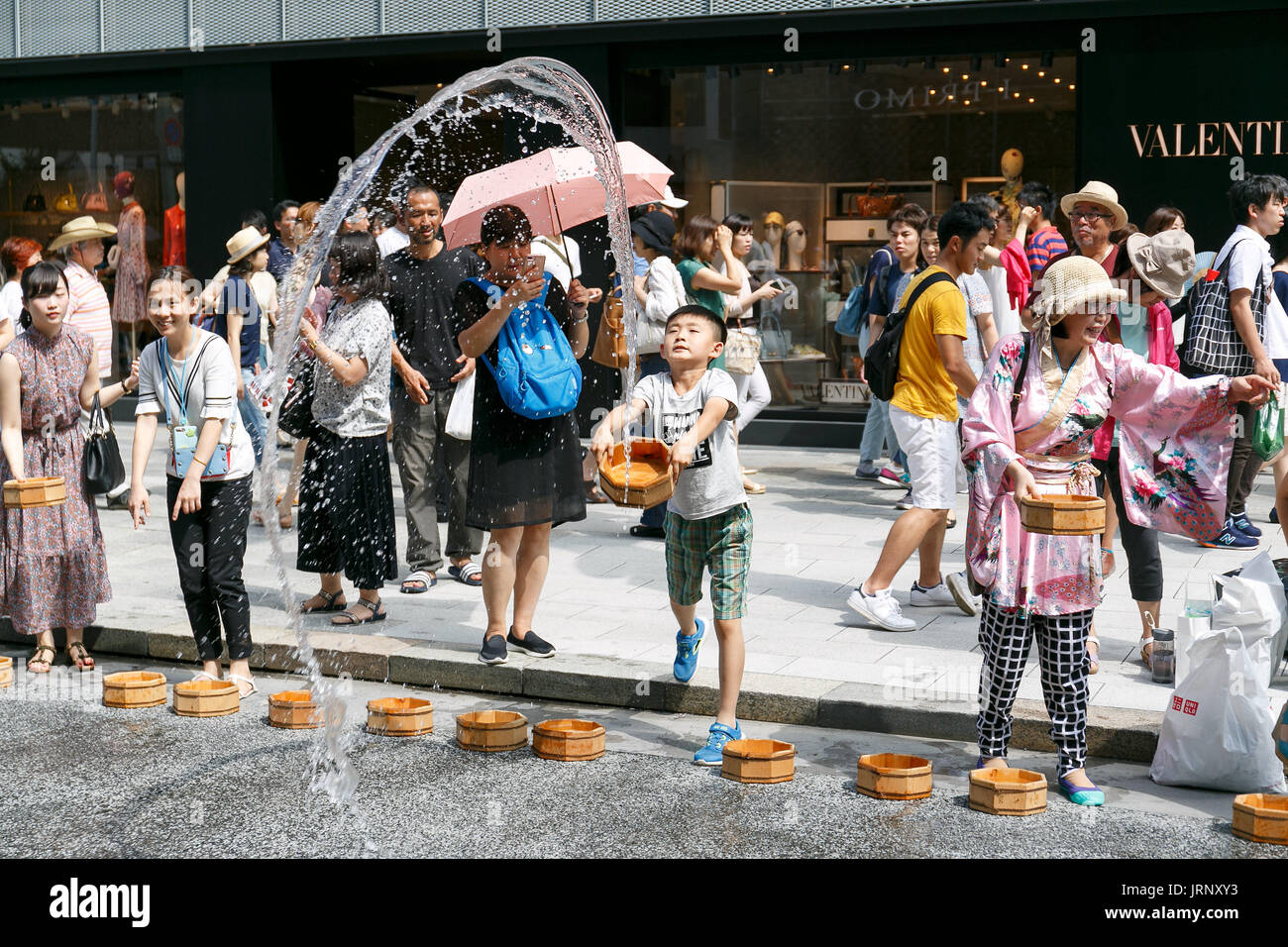 Tokyo, Japan. 6th August, 2017. A boy sprinkles water on the pavement ...