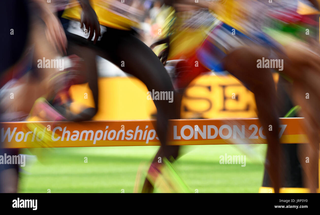 Athletes pass the first hurdle during the first heat of the men's 3,000 ...