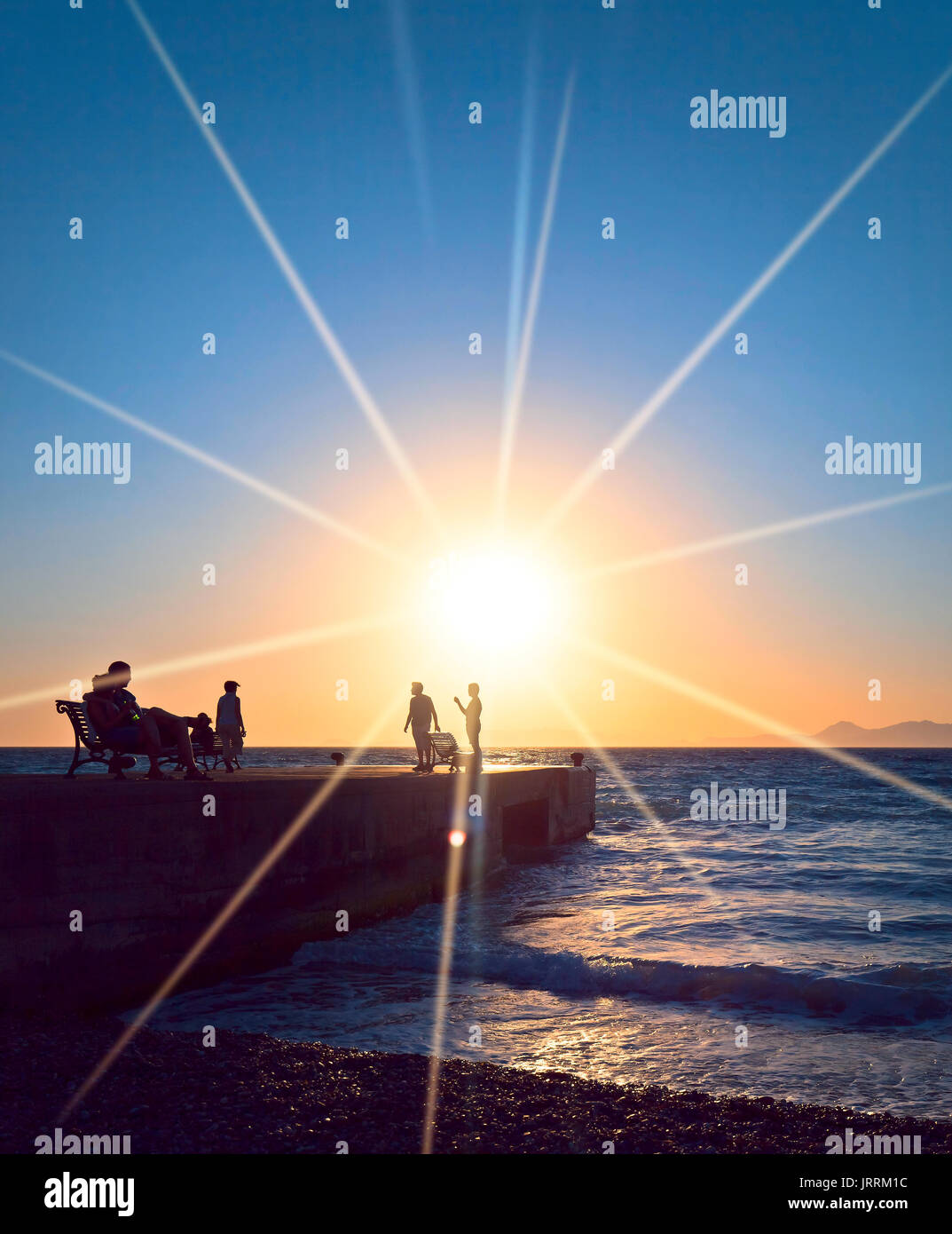 Silhouettes of people relaxing at sunset. Sunset on the Mediterranean ...