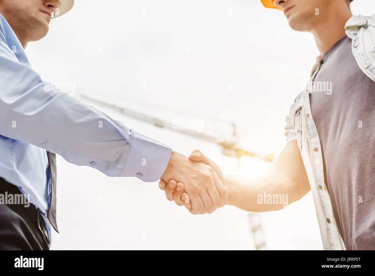 Architect engineer shaking hands other hand at construction site ...