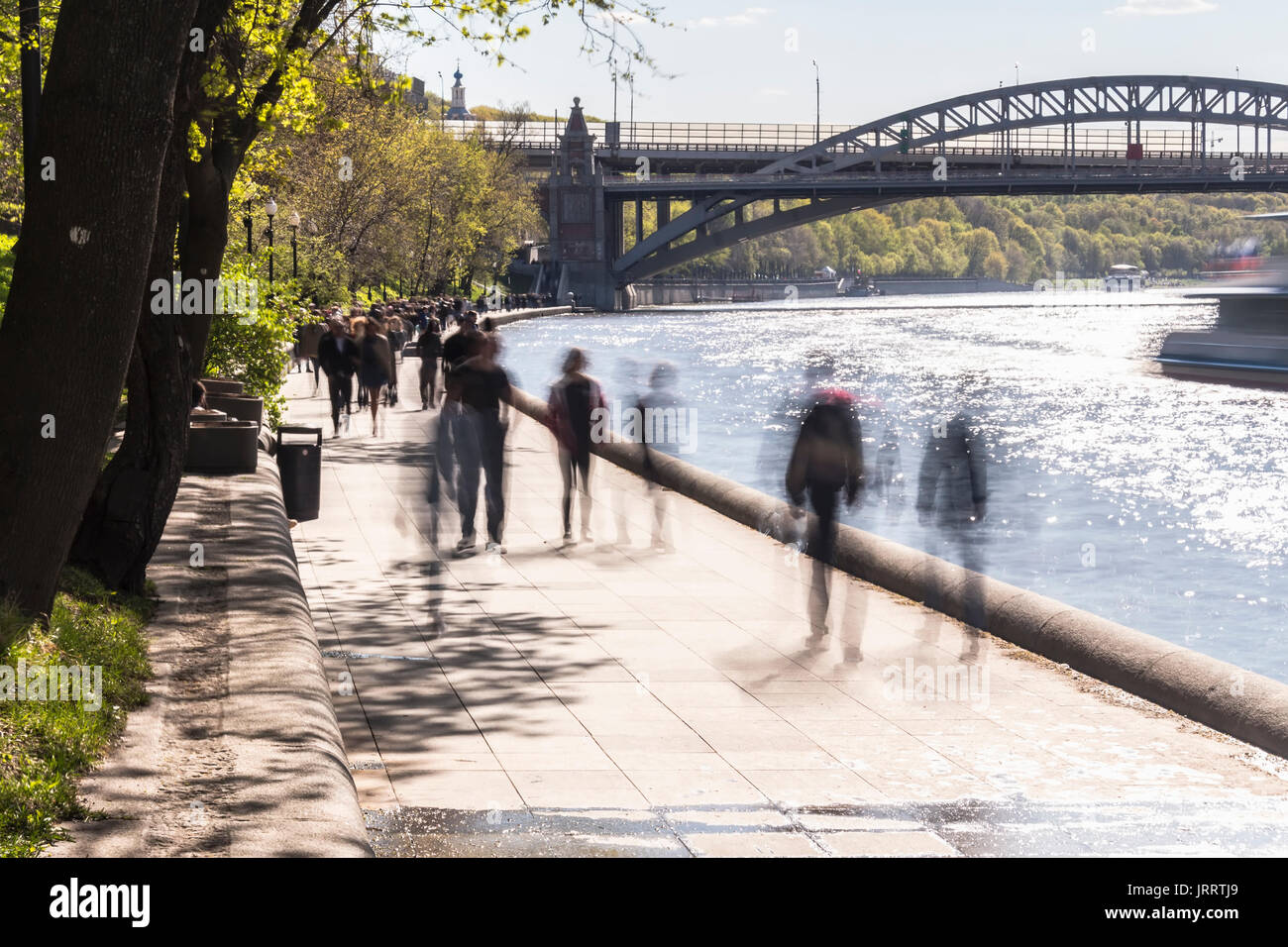 silhouettes of people walk along the embankment of a city river Stock ...