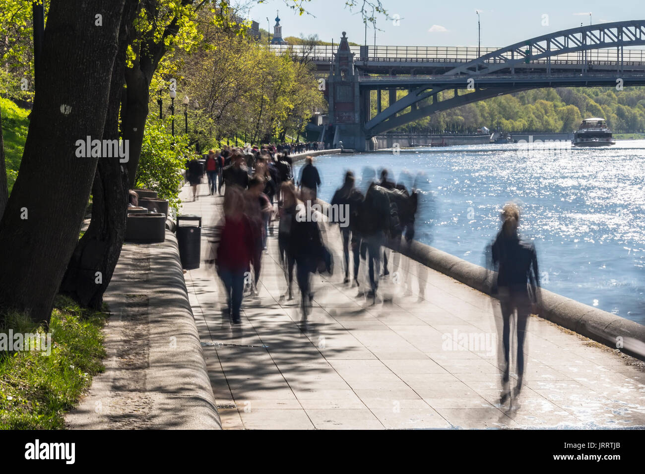 silhouettes of people walk along the embankment of a city river Stock ...