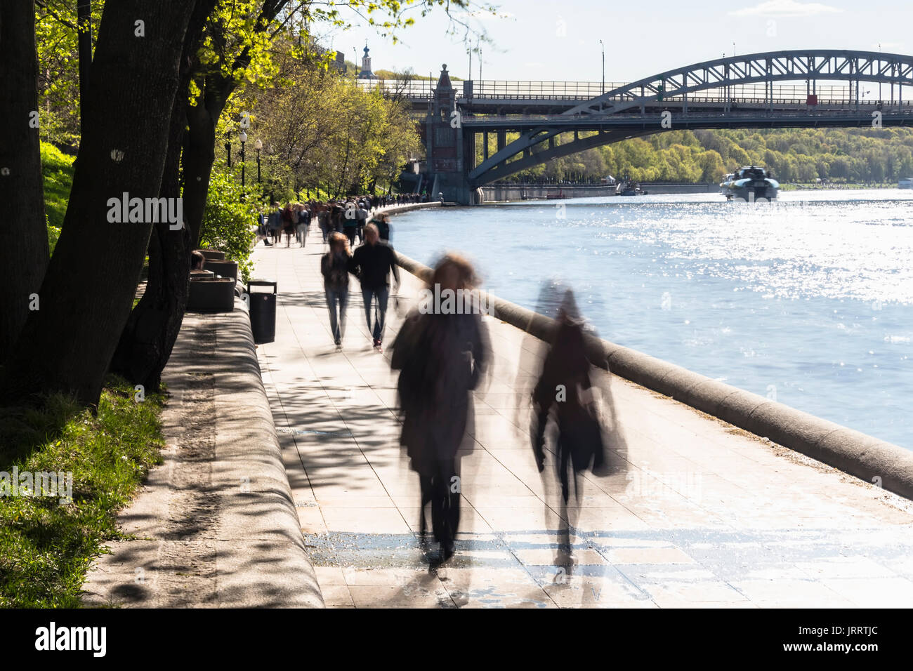silhouettes of people walk along the embankment of a city river Stock ...