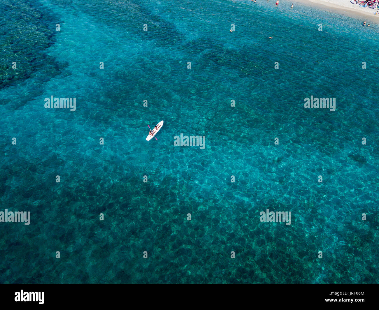 Aerial view of a canoe in the water floating on a transparent sea ...