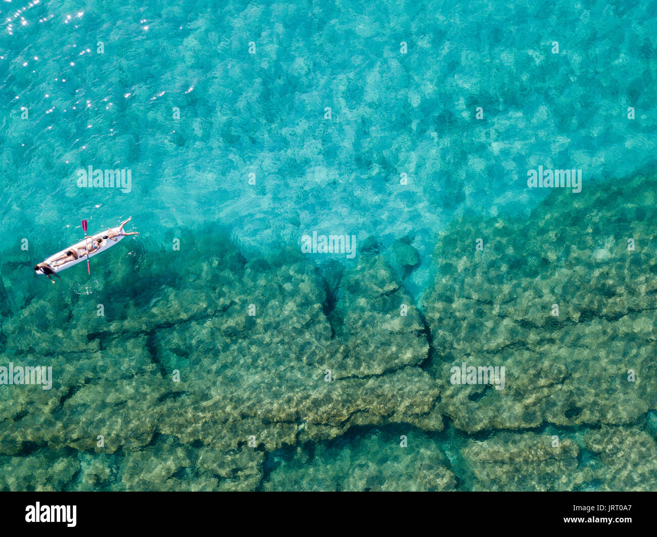 Aerial view of a canoe in the water floating on a transparent sea ...