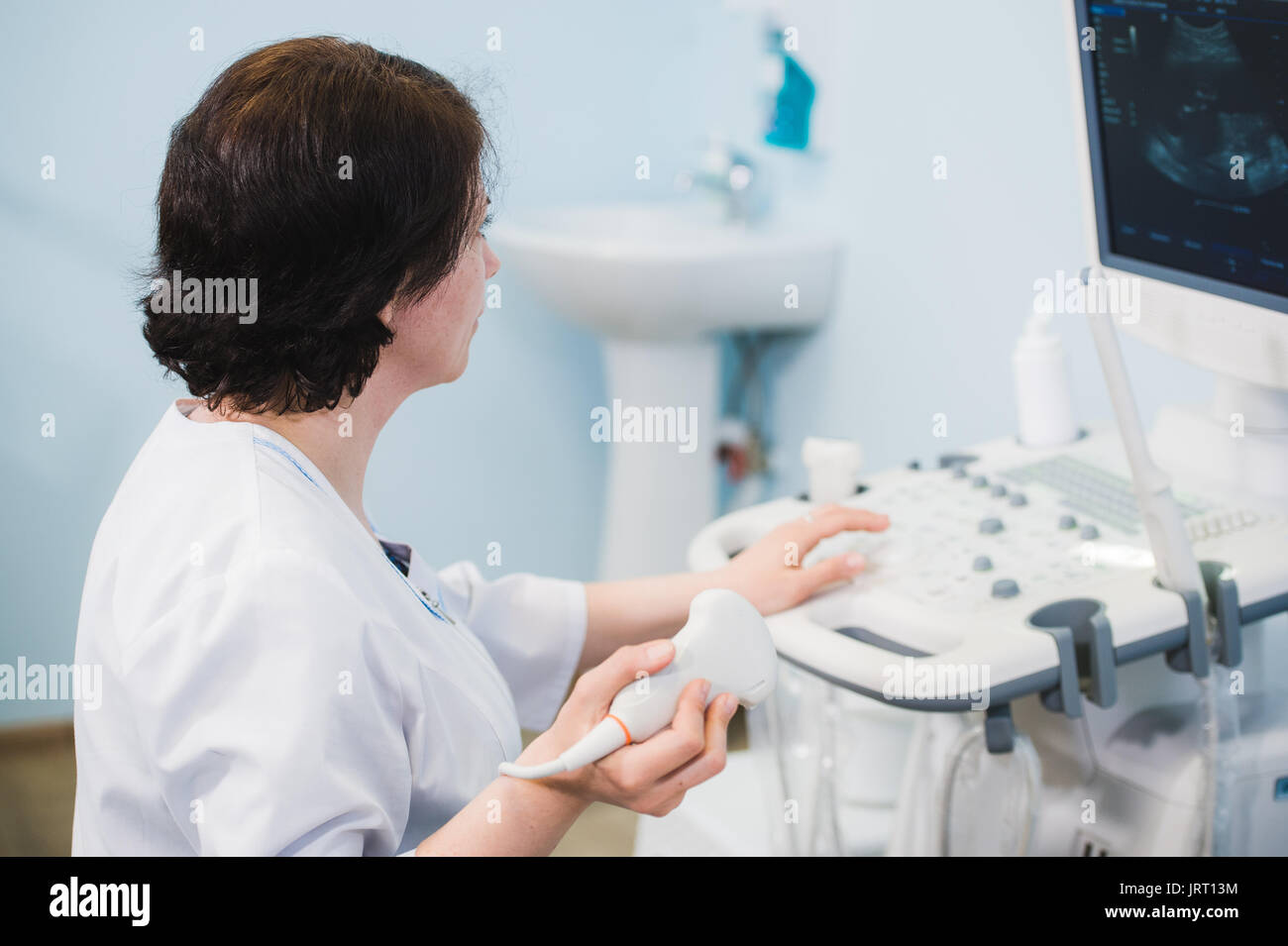 Happy mature female doctor using ultrasound scanner. Echography machine ...