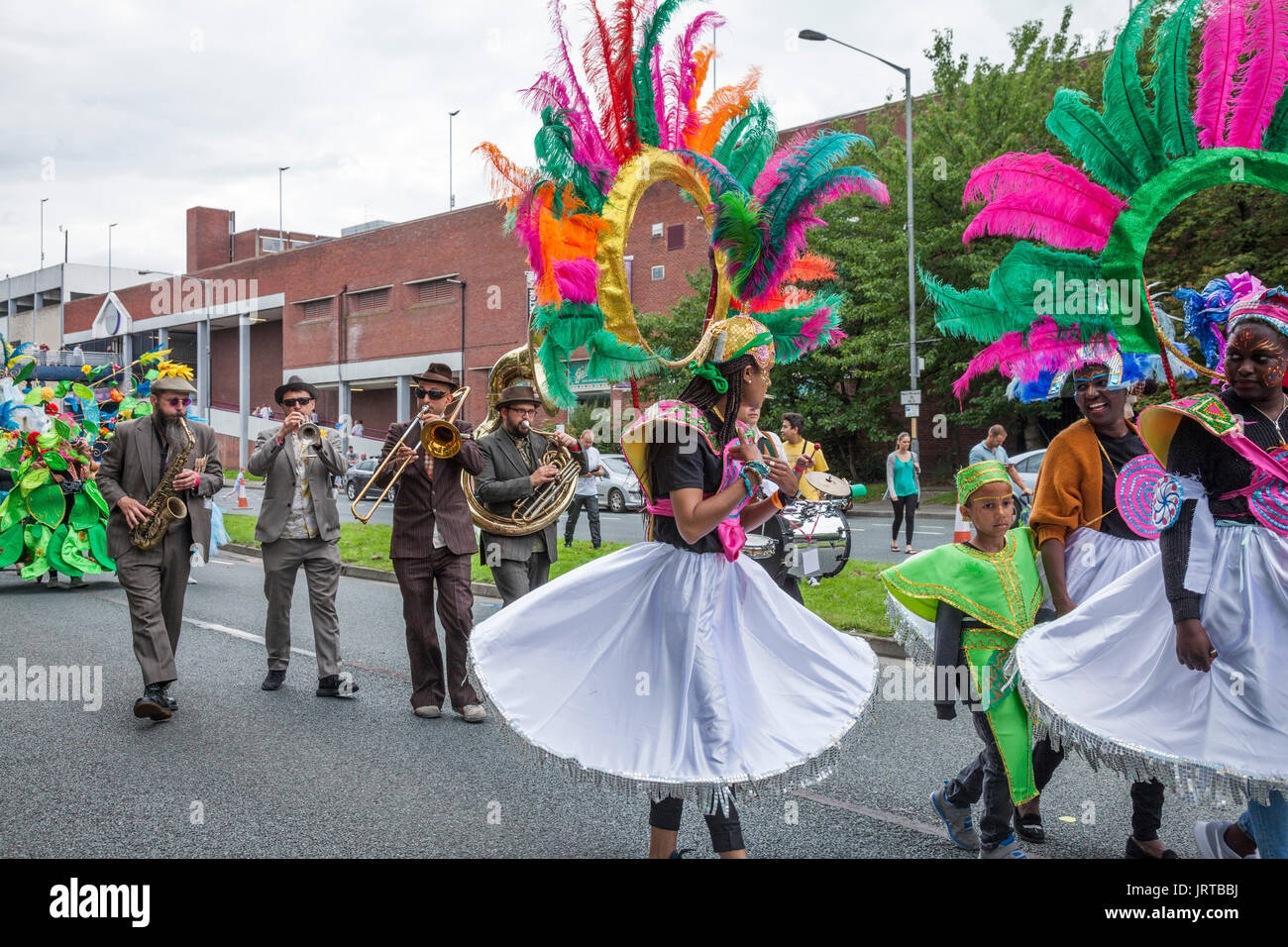 People in colourful outfits and a jazz band walk down the Riverside ...