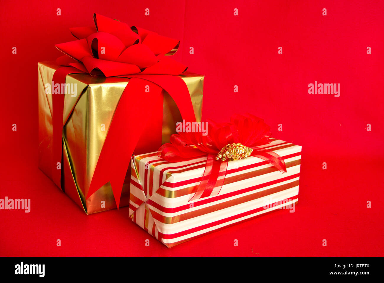 A gold foil-wrapped gift and a red, gold and white-wrapped gift are ...