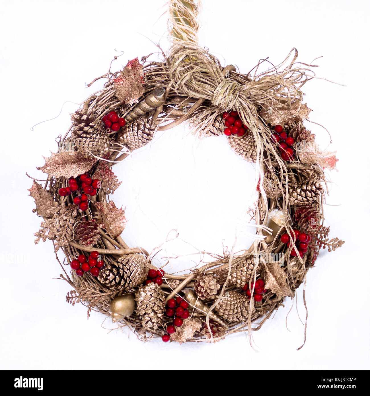 A natural twig wreath is decorated with pine cones, red berries, gold ...