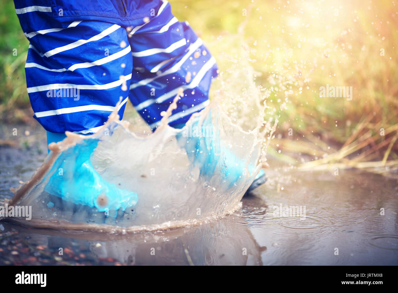 Child walking in wellies in puddle on rainy weather. Boy under rain in ...