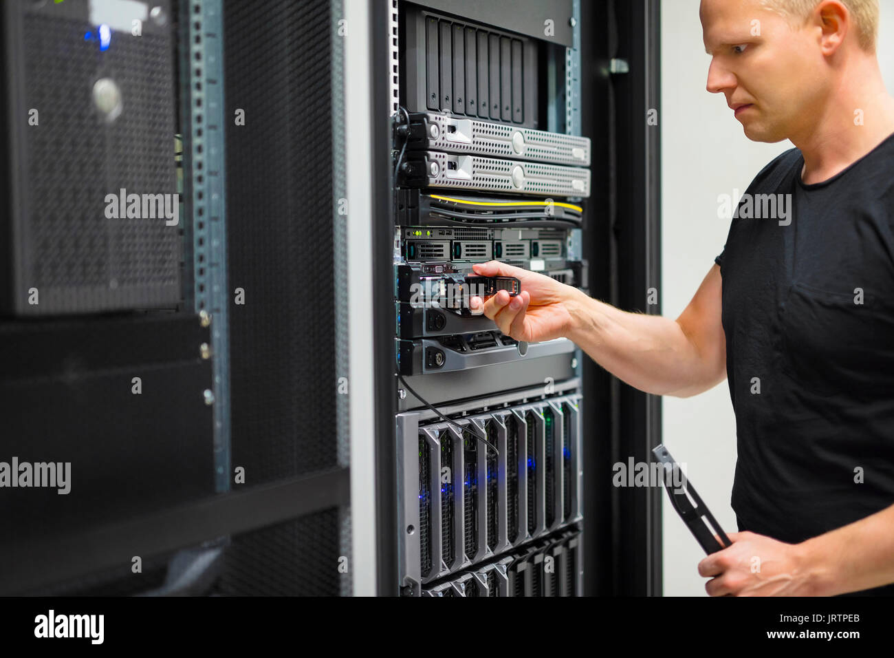 Confident mid adult male IT engineer installing hard drive in rack ...