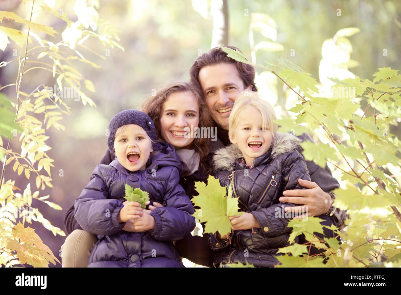 Portrait of happy smiling family with two children relaxing in autumn ...