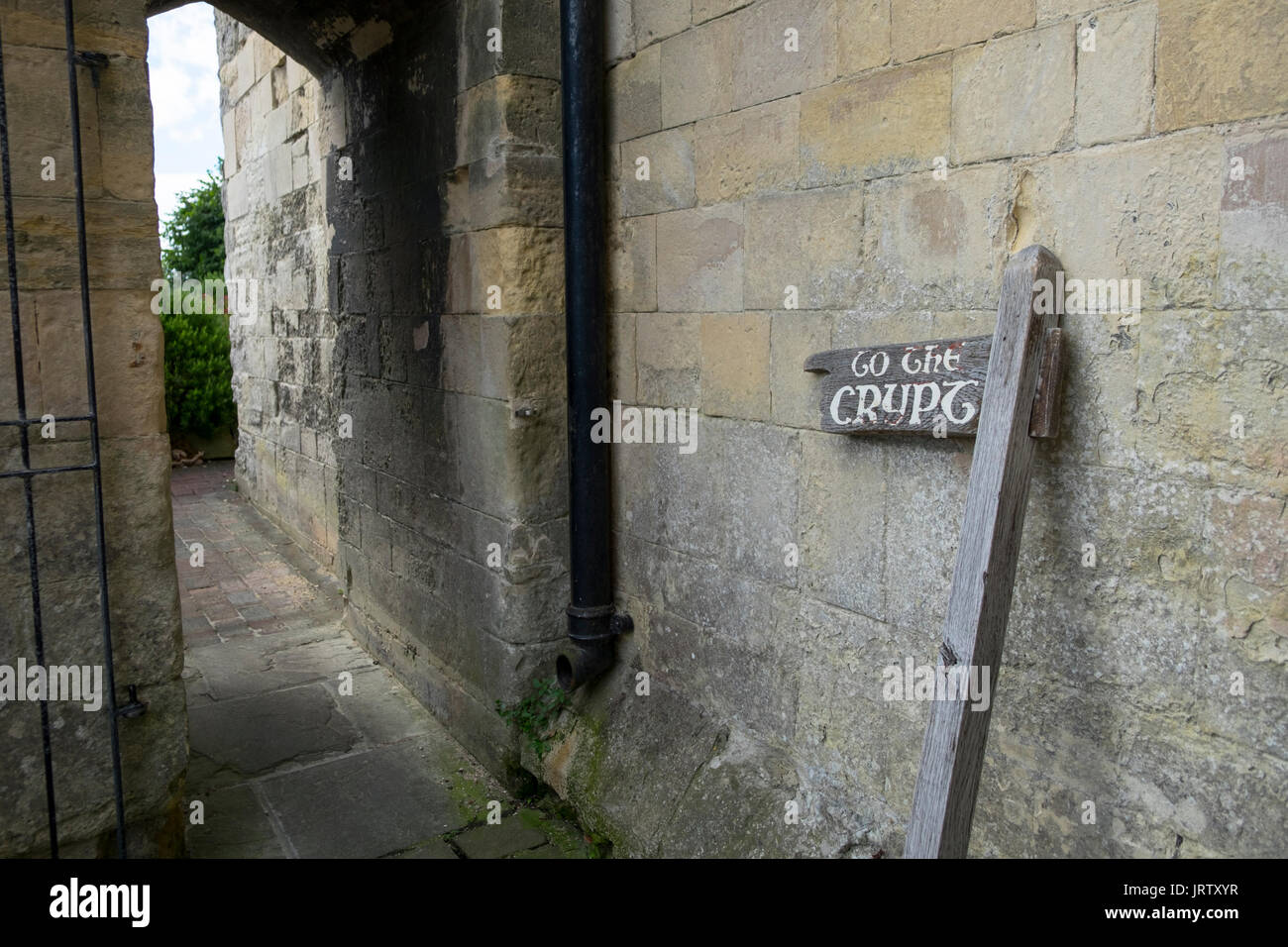 wooden sign leaning on an ancient church wall depicting 'to the crypt ...
